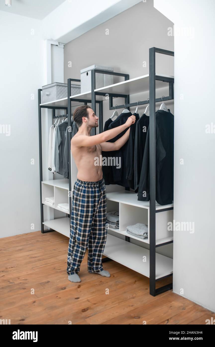 Dark-haired young man choosing clothes in his wardrobe Stock Photo - Alamy