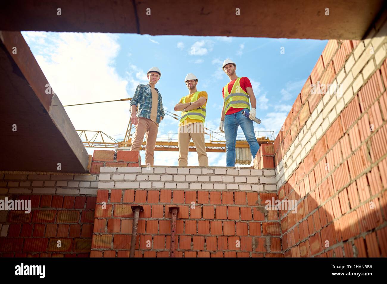 Bottom view of men standing on building under construction Stock Photo ...