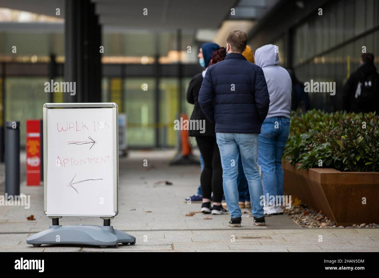 People queue next to a sign for walk-ins and appointments at the COVID ...