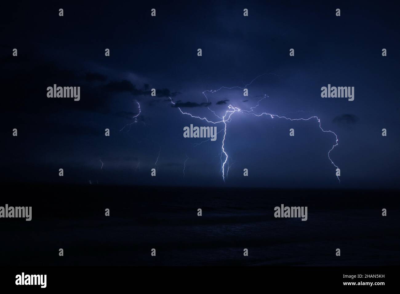 Flash of lightning over the sea thunderstorm clouds Stock Photo - Alamy