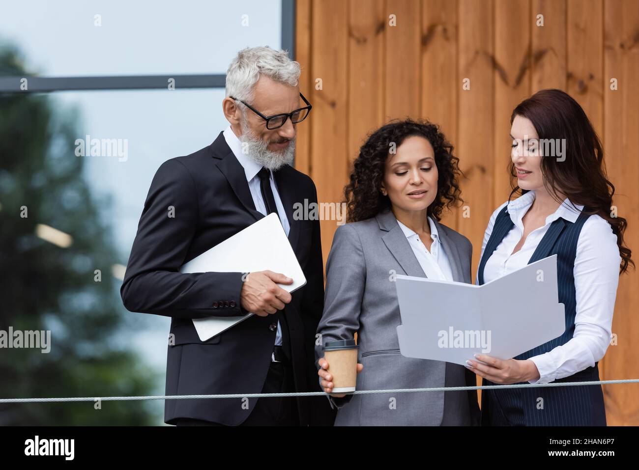 real estate agent showing documents to interracial business partners ...