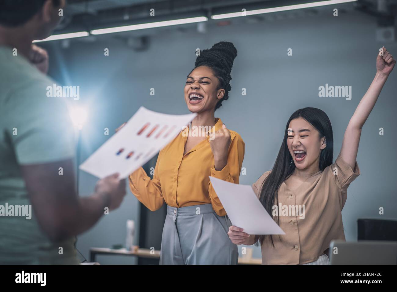 Emotional african american and asian girls rejoicing in office Stock ...