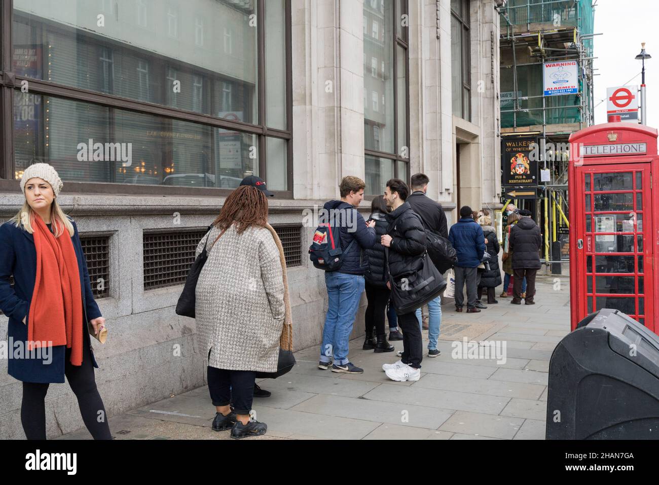 holiday makes Queue on pavement with red telephone box for passport ...