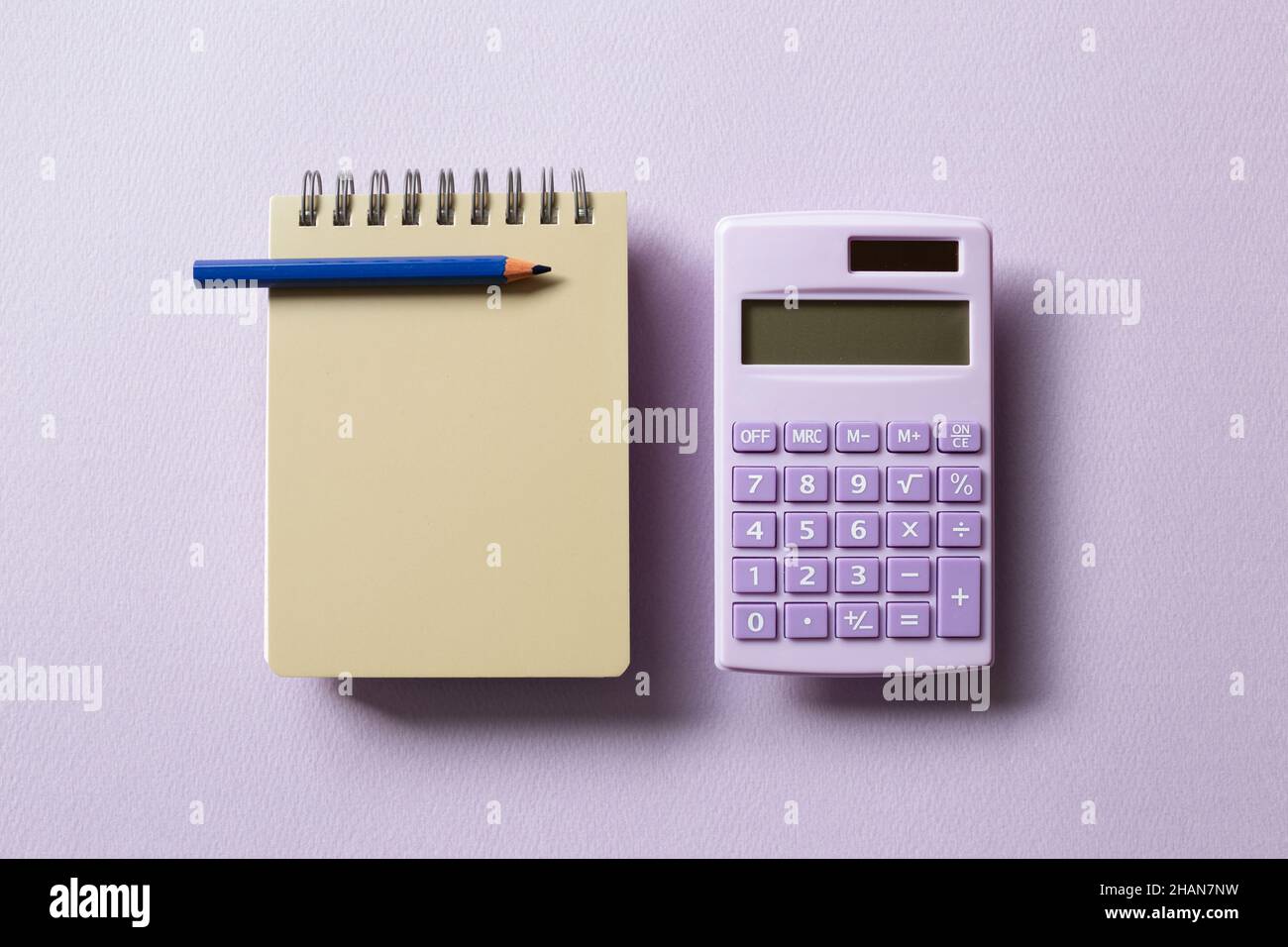 Beige notepad and calculator isolated on purple background. top view ...