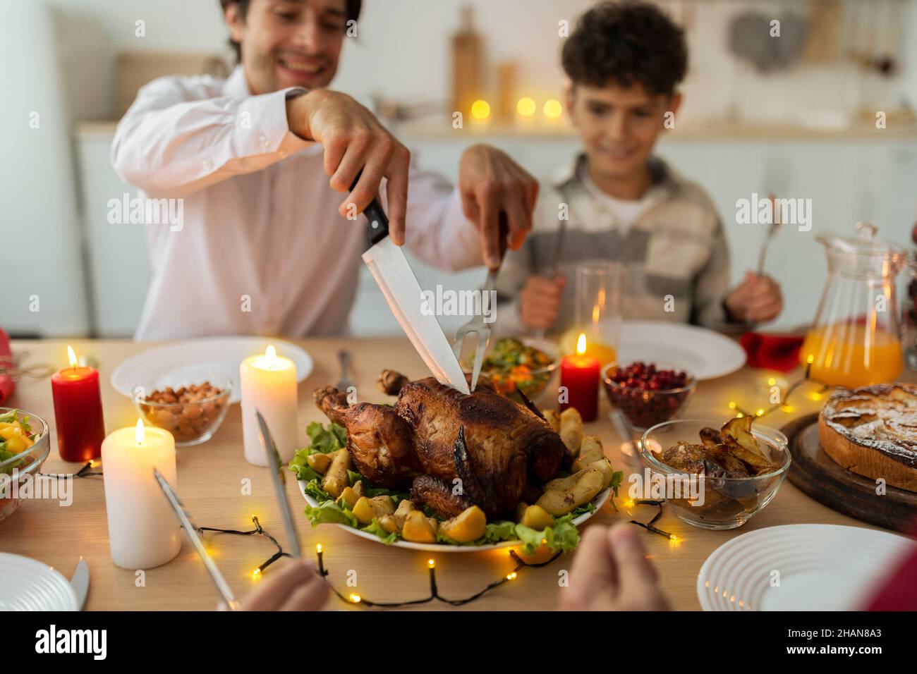 Happy father cutting roasted Christmas turkey for his son and family at ...