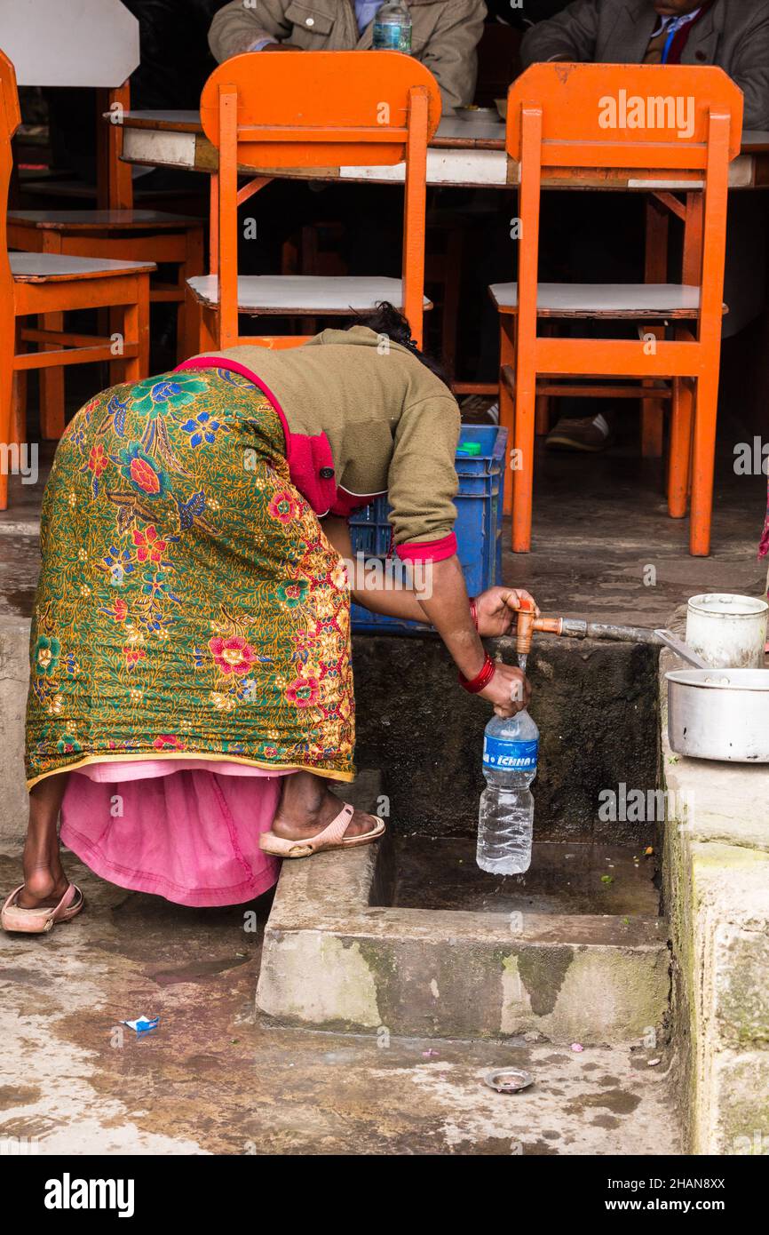 A Nepali woman hills her plastic water bottle from a tap in Malekhu ...