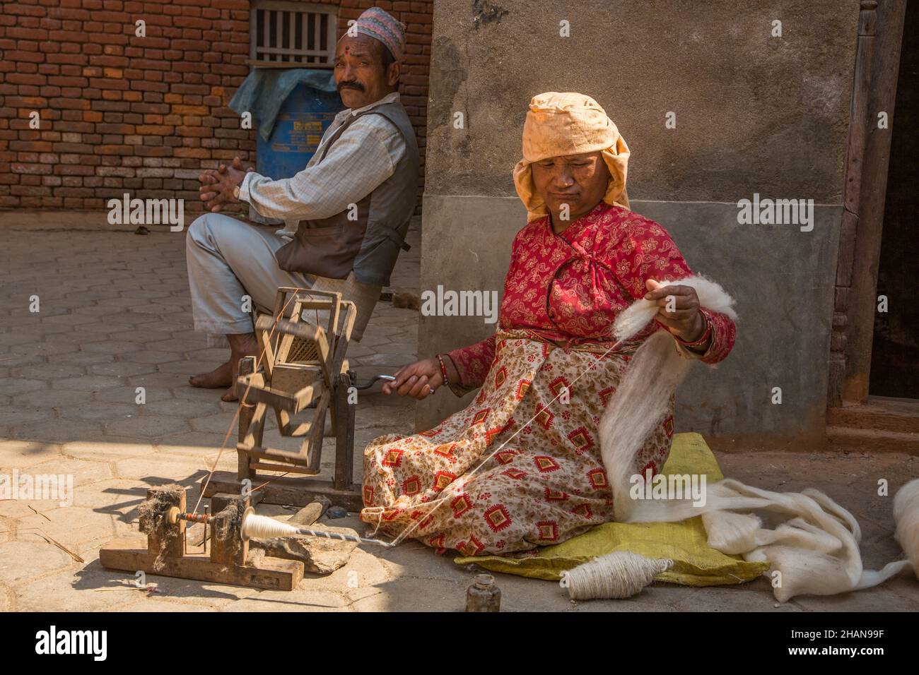 A Nepali woman spins wool thread with a hand-cranked spinning wheel in ...