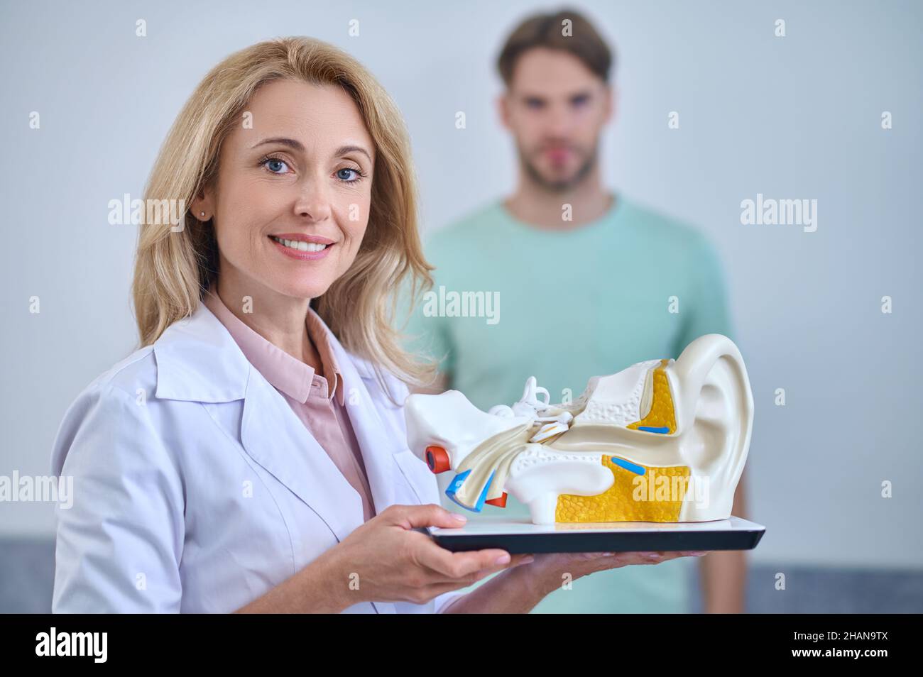Smiling woman showing human ear model Stock Photo - Alamy