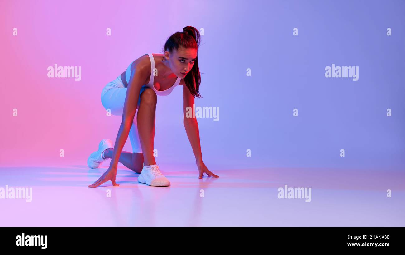 Fit Sportswoman Doing Crouch Start Ready For Running, Neon Background ...