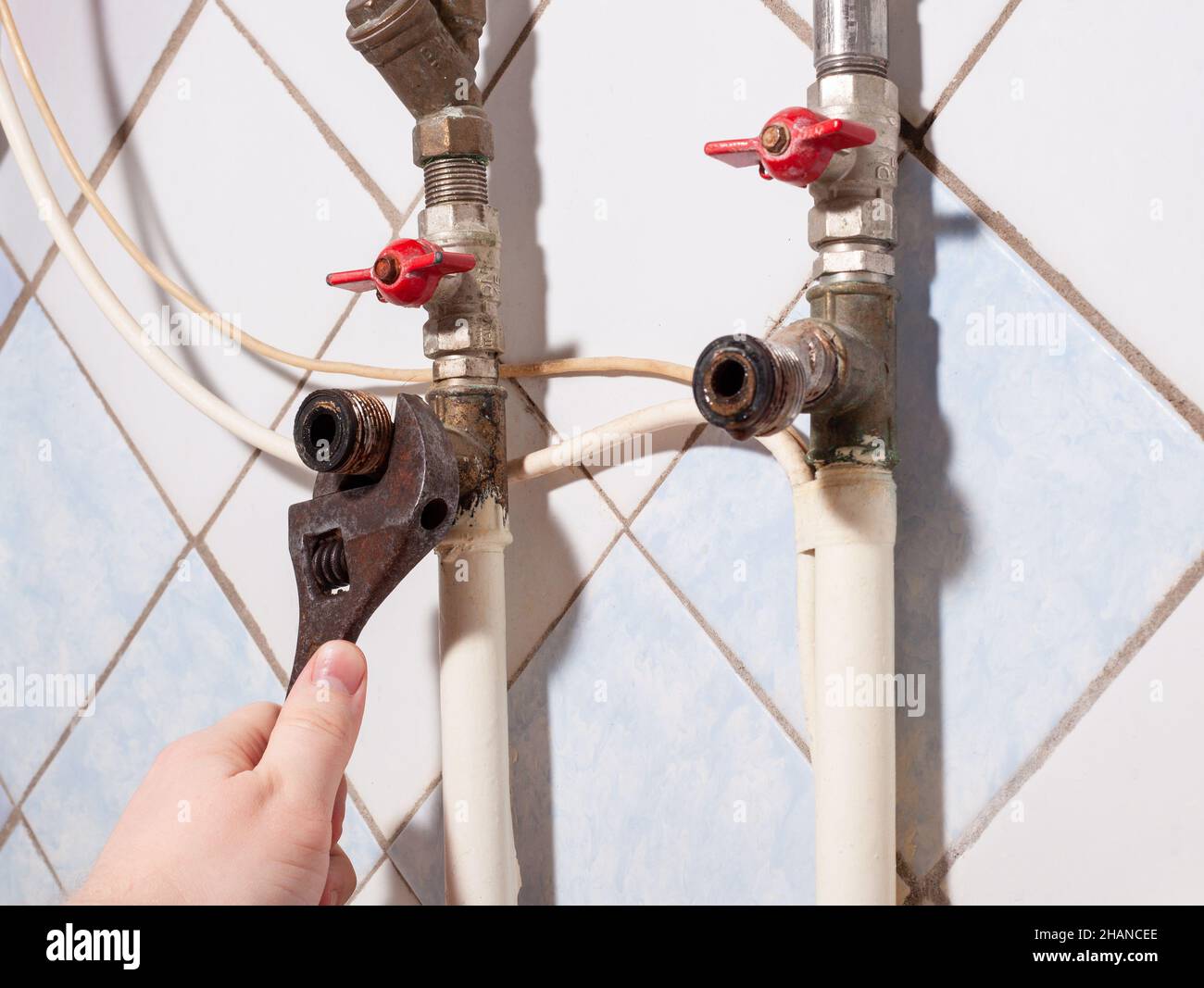 Unscrewing plumbing fittings on water pipeline by old adjustable wrench ...