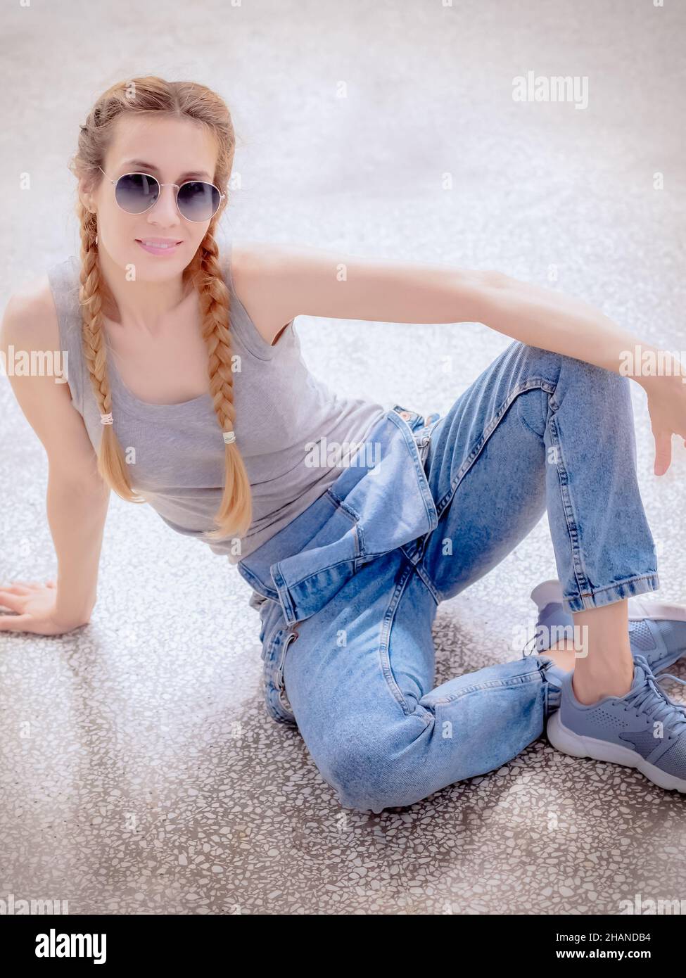 Portrait of fair-haired lady with two pigtails sits with her feet ...