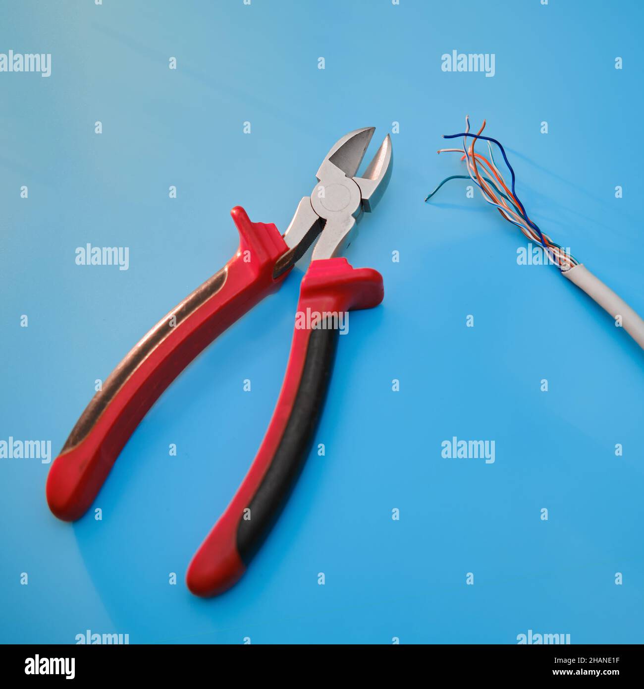 Cutting a computer network wire with wire cutters, blue studio ...