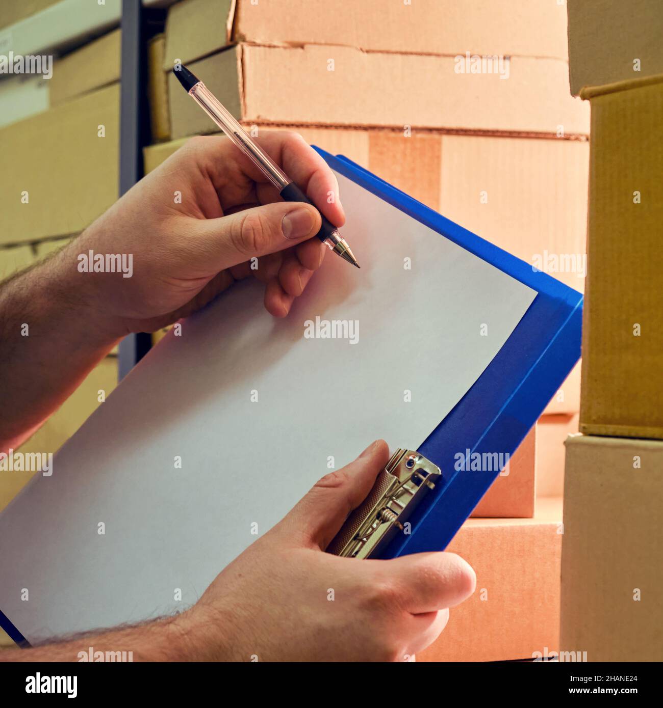 Inventory in a warehouse with goods in boxes, a man hands with a pen on ...