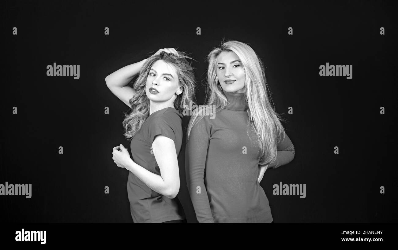 Portrait of pretty women friends posing against black background Stock ...