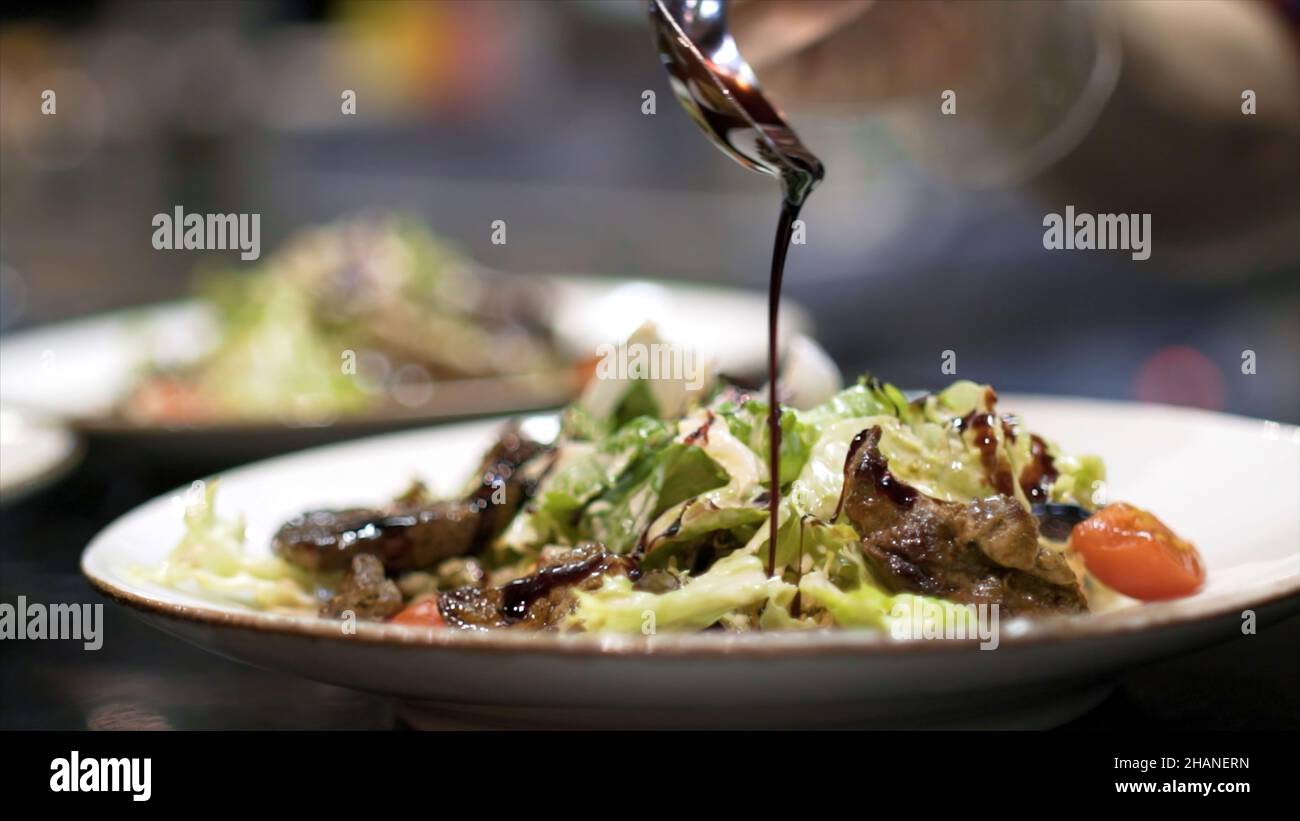 Spoon with sauce is poured over salad. Action. Closeup of aesthetic ...