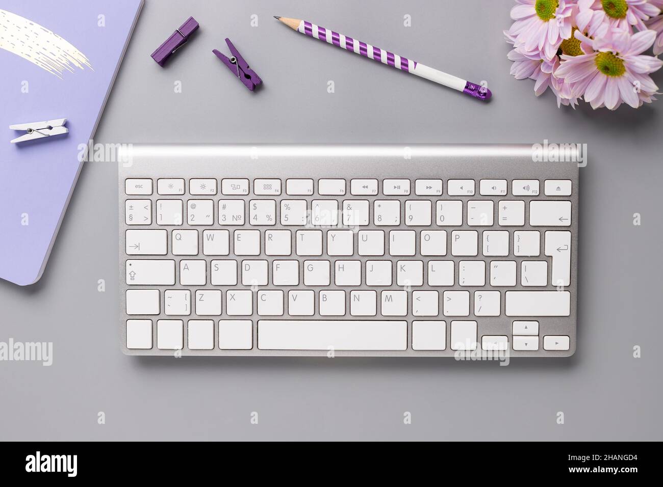 Home office workspace with keyboard, notebook, stationery and flowers ...