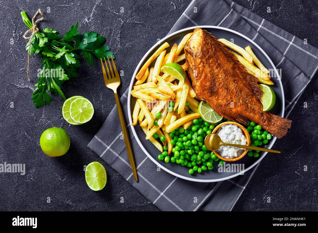 fried Atlantic redfish on a plate with potato chips, boiled green peas ...