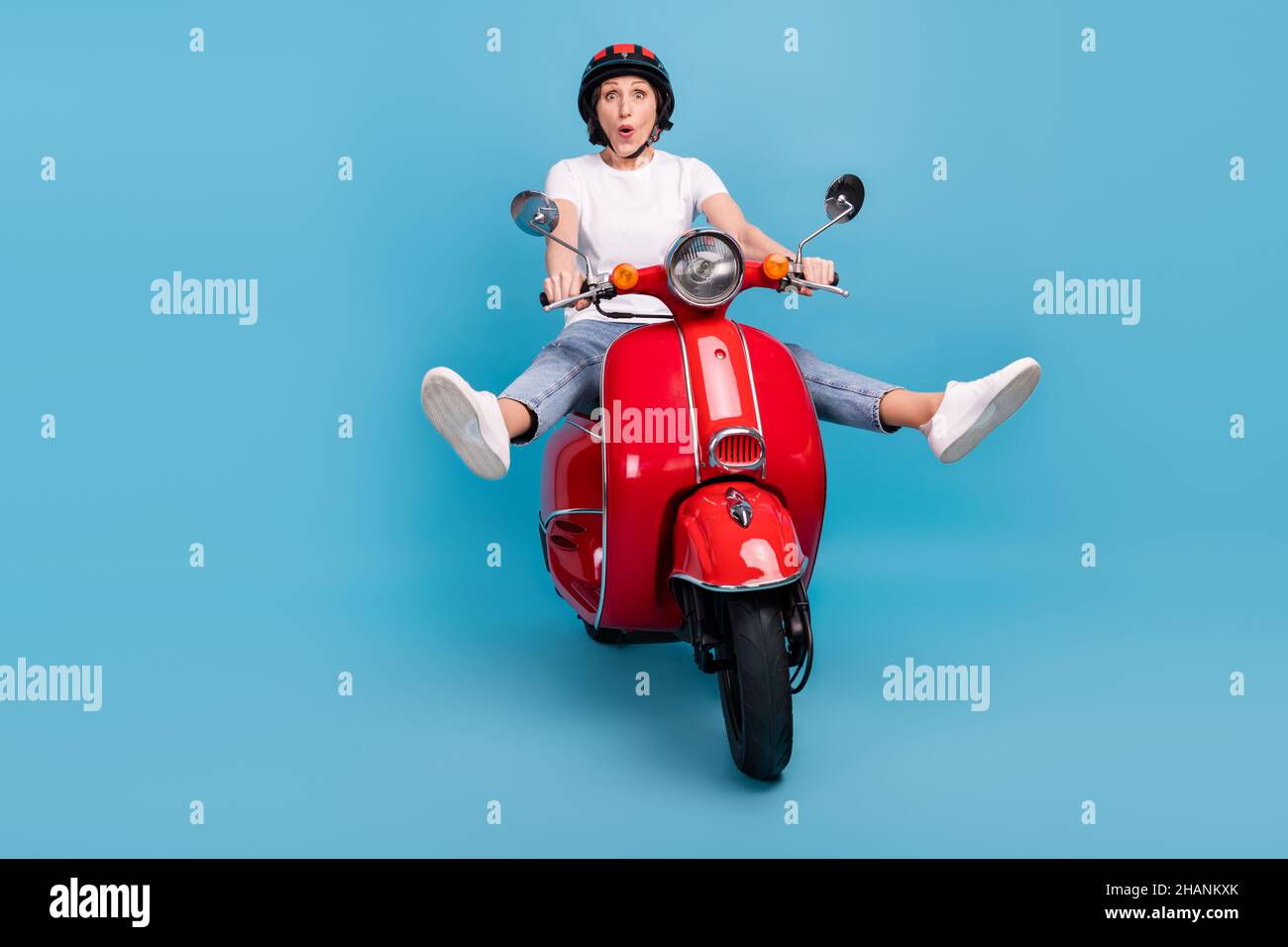 Portrait of attractive amazed childish woman riding moped having fun ...