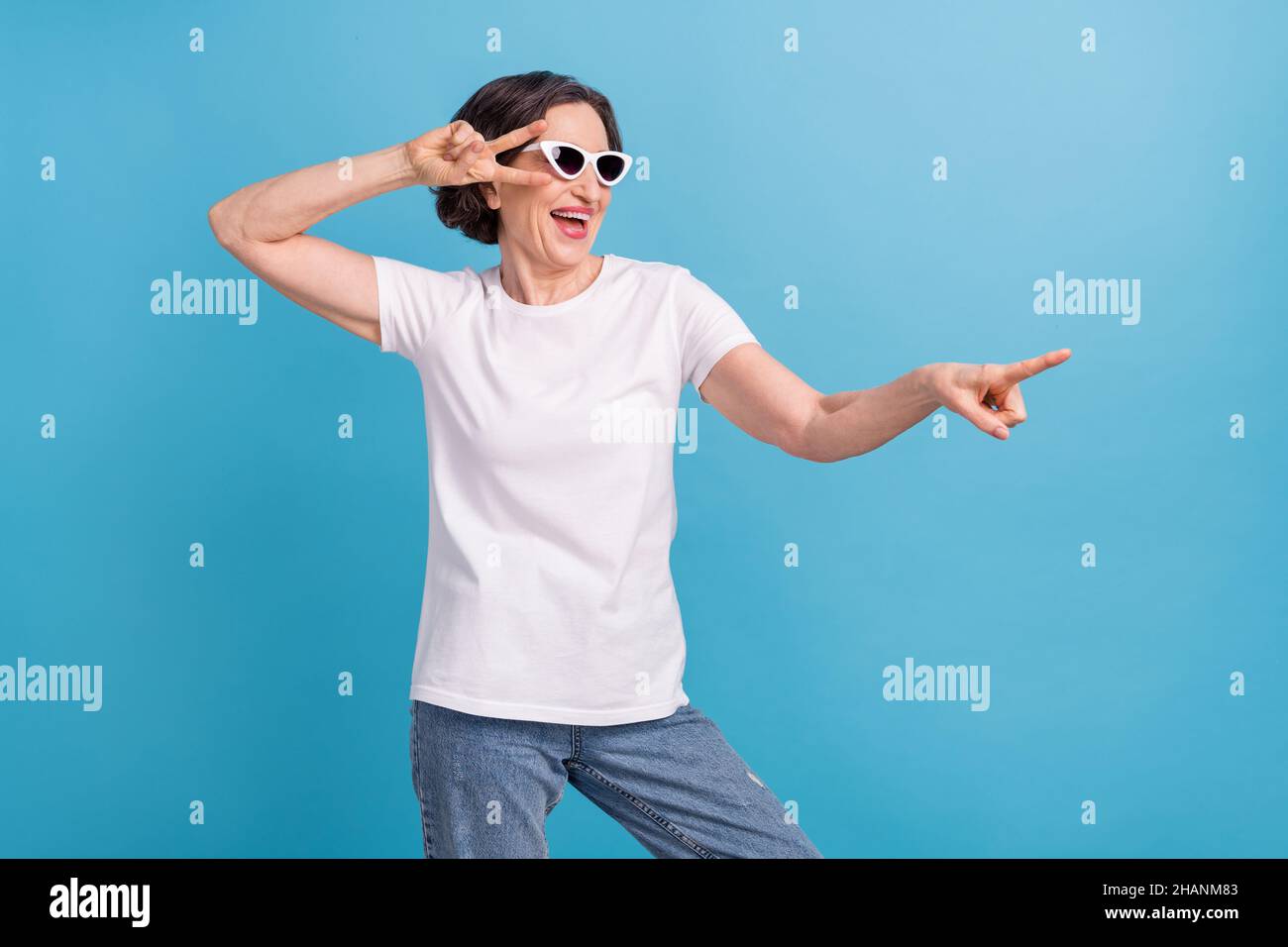 Portrait of attractive cheerful woman dancing having fun showing v-sign ...