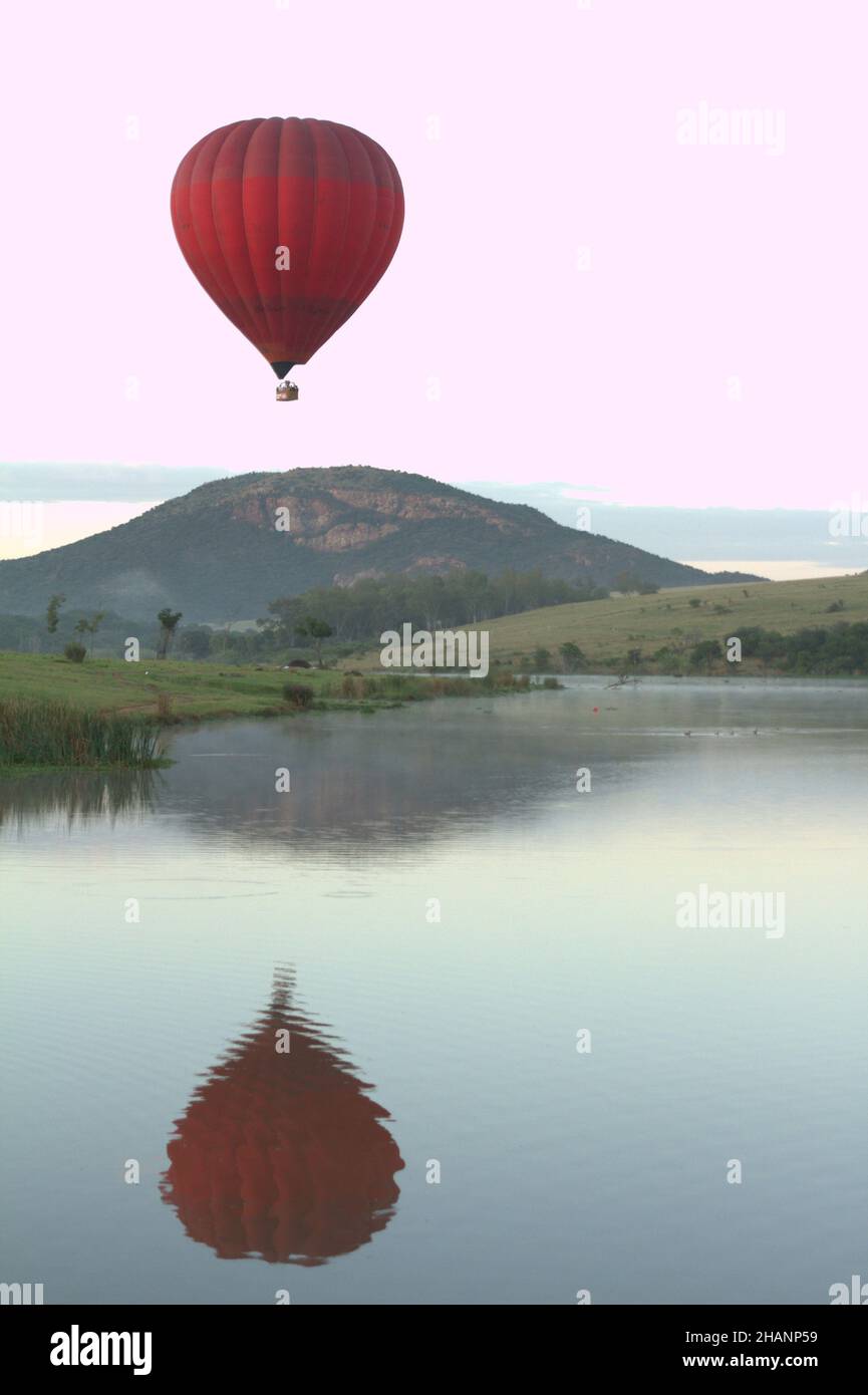Red hot air balloon flying above a lake on a misty morning Stock Photo ...