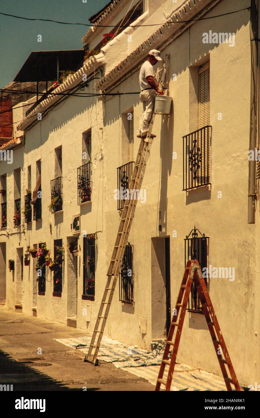 Commercial painter working off long steep ladder in the tourist town of ...