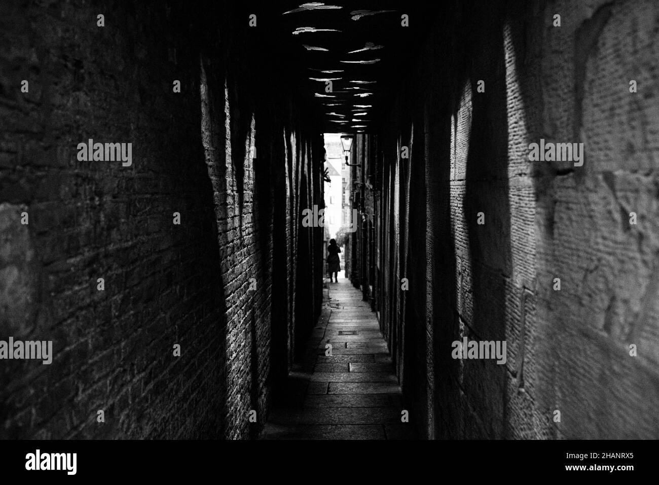 Grayscale shot of a person crossing a narrow dark tunnel Stock Photo ...