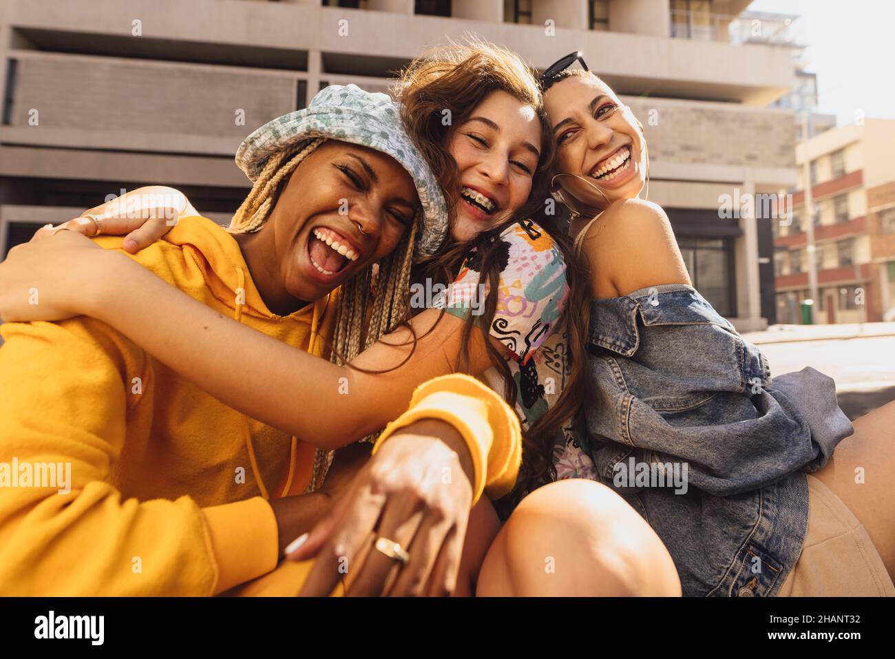 Three female friends laughing together outdoors. Group of generation z ...