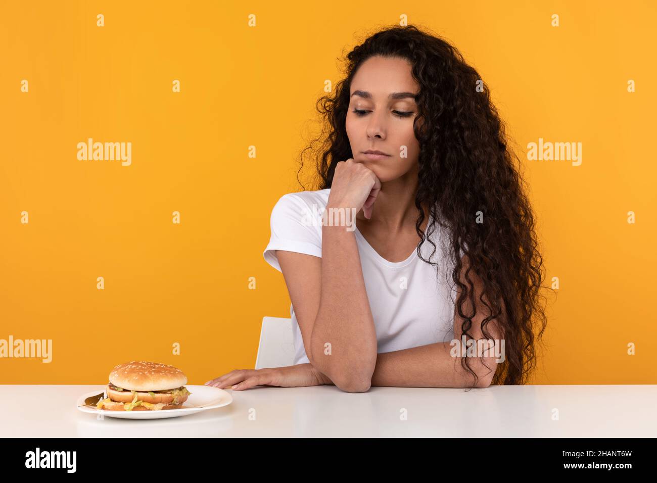 Sad Young Lady Looking At Burger And Thinking Stock Photo - Alamy