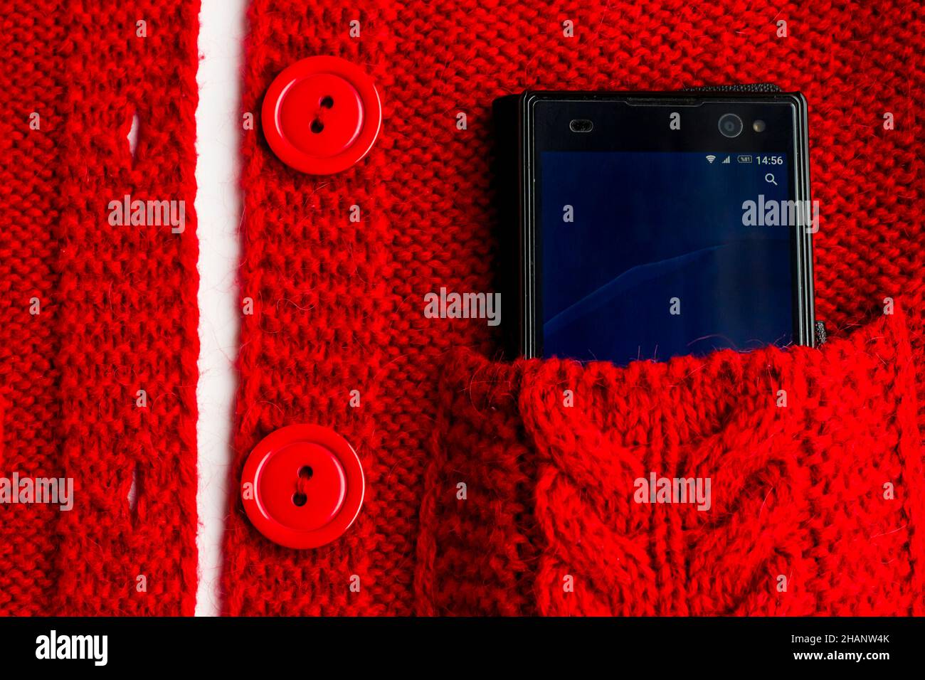 Smart mobile phone with blank screen in pocket of red color knit wool ...