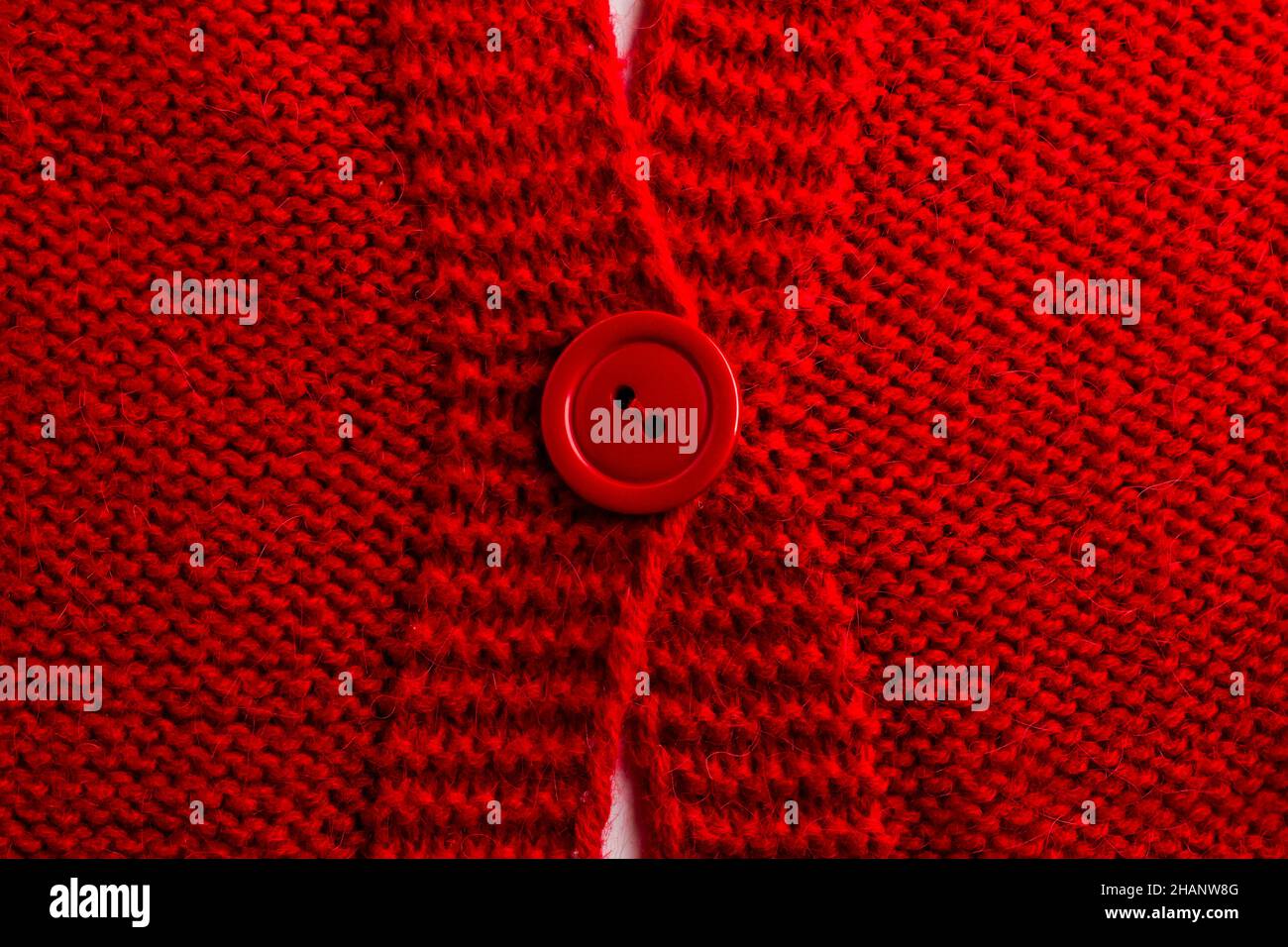 Hand knitted red color wool sweater,on the white surface.Close-up taken ...