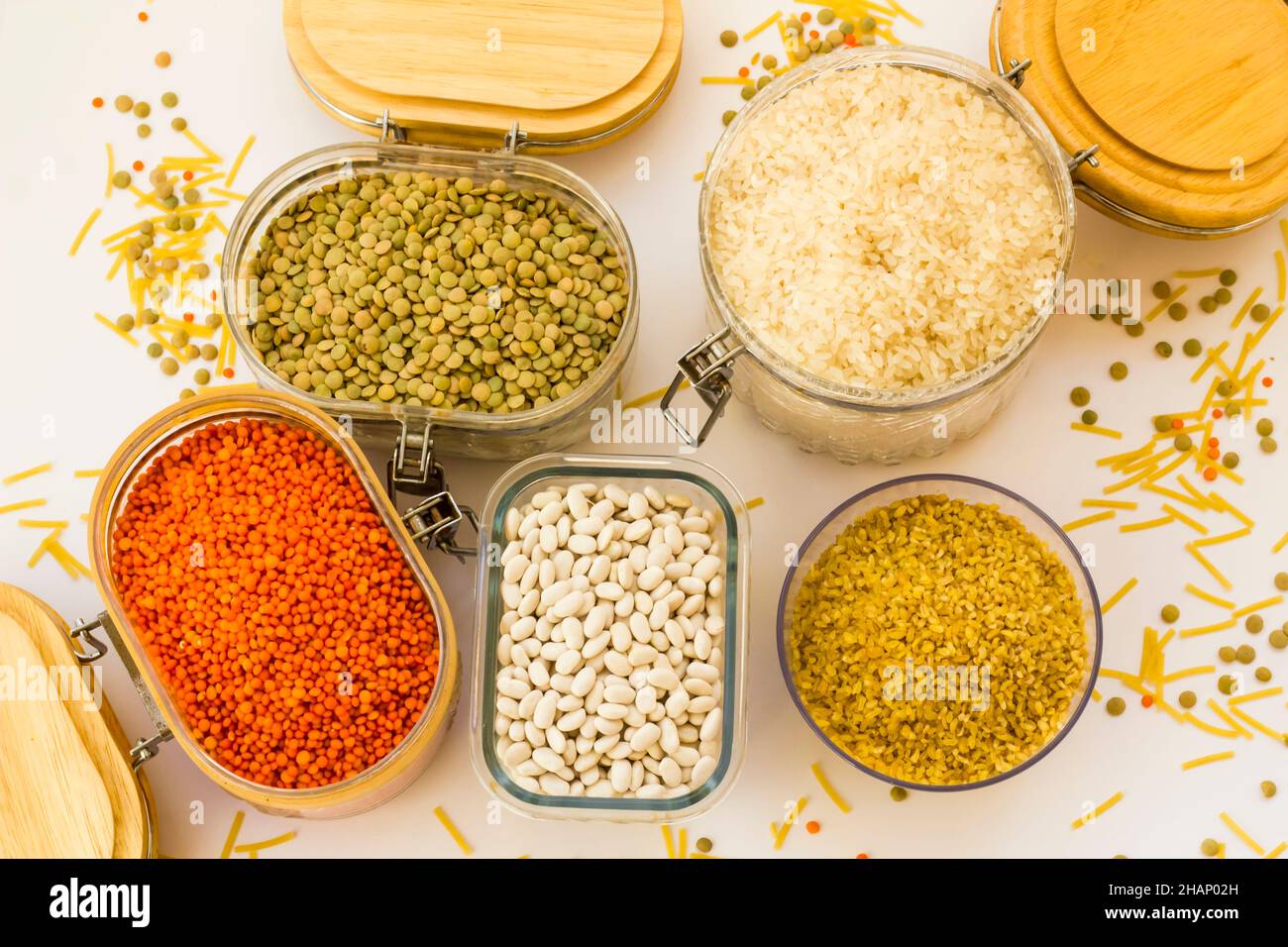 Uncooked dry cereal food group in glass containers on white,above view ...