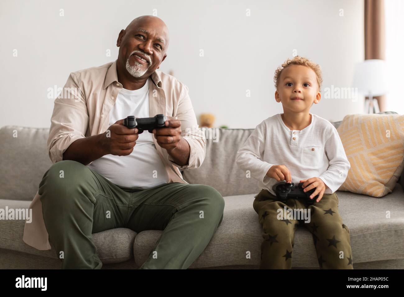 Cheerful African American Grandpa And Grandson Playing Videogame At ...