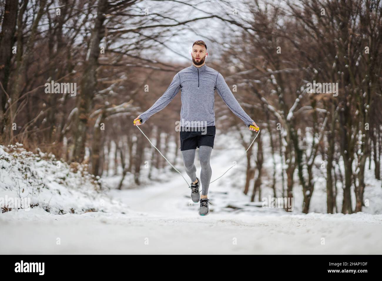 Fit sportsman skipping the rope in nature at snowy winter day. Winter ...