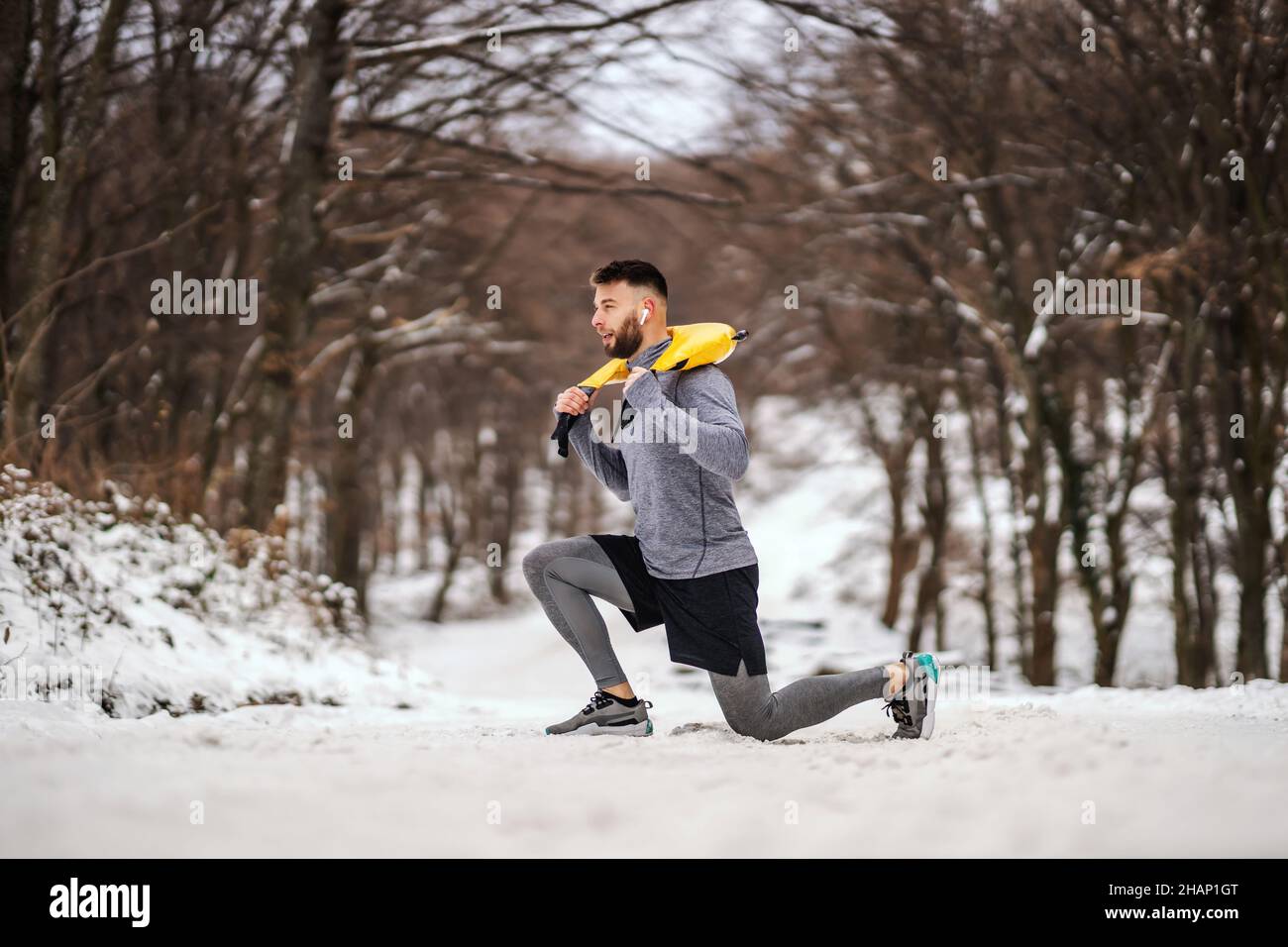 Side view of bodybuilder lifting weights on snowy weather in nature ...