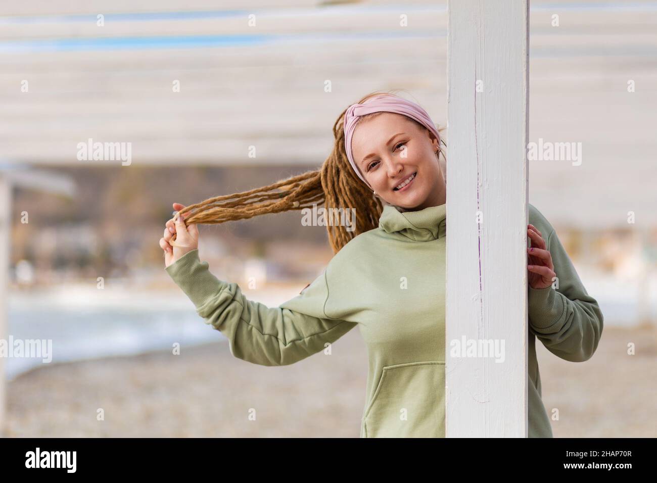 Portrait of a young funny woman with dreadlocks posing against a ocean ...