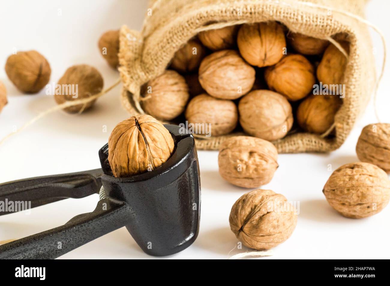 A sack of walnuts on white background with walnut cracker and copy ...