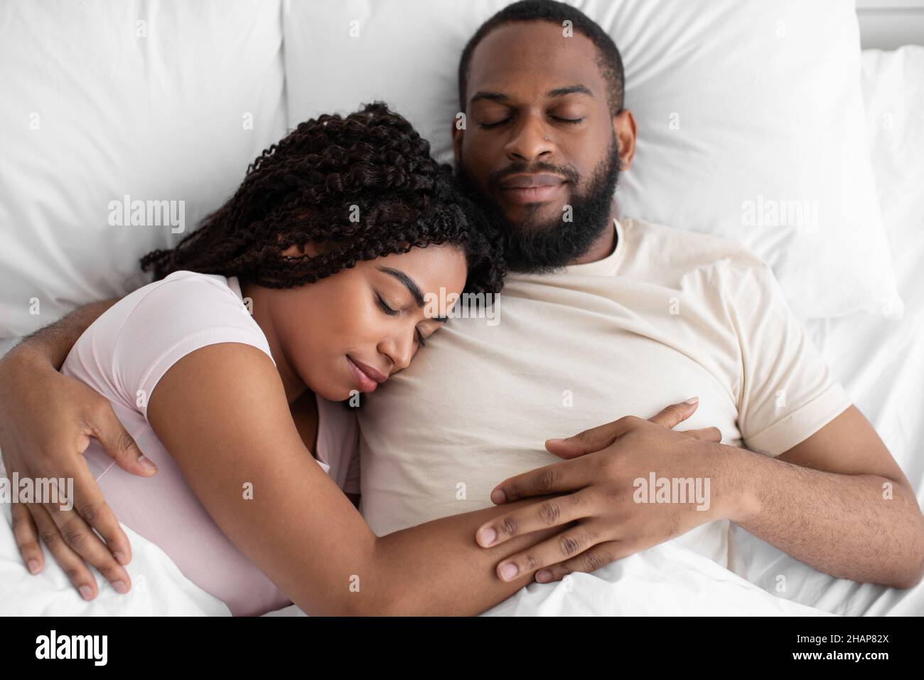 Calm young african american guy and woman sleeping, hugging on white ...