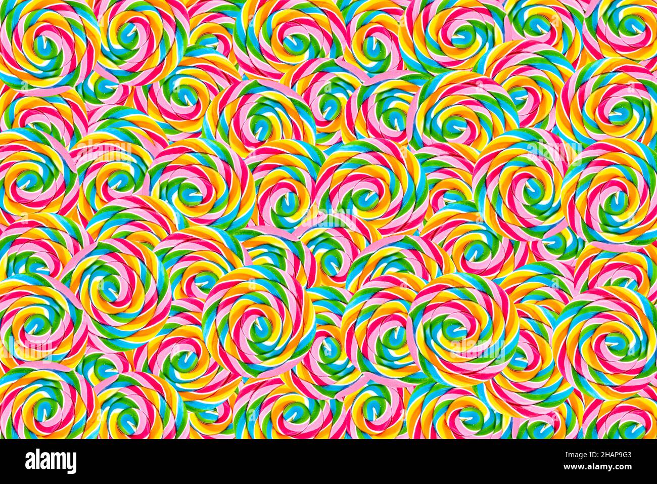 Background made of multi-colored spiral rainbow lollipops, top view ...