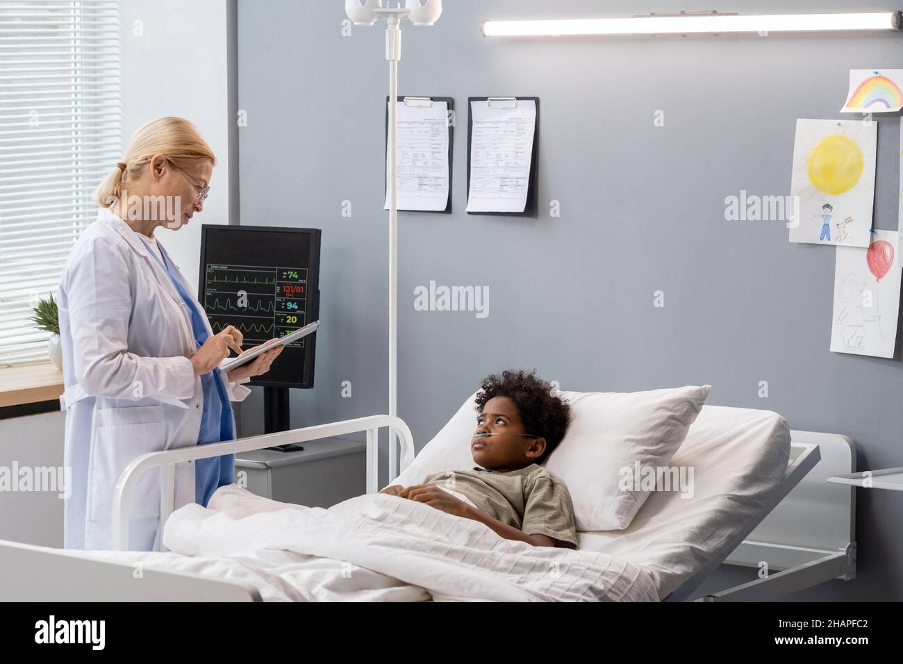 Female doctor in white coat asking questions to little boy and making ...