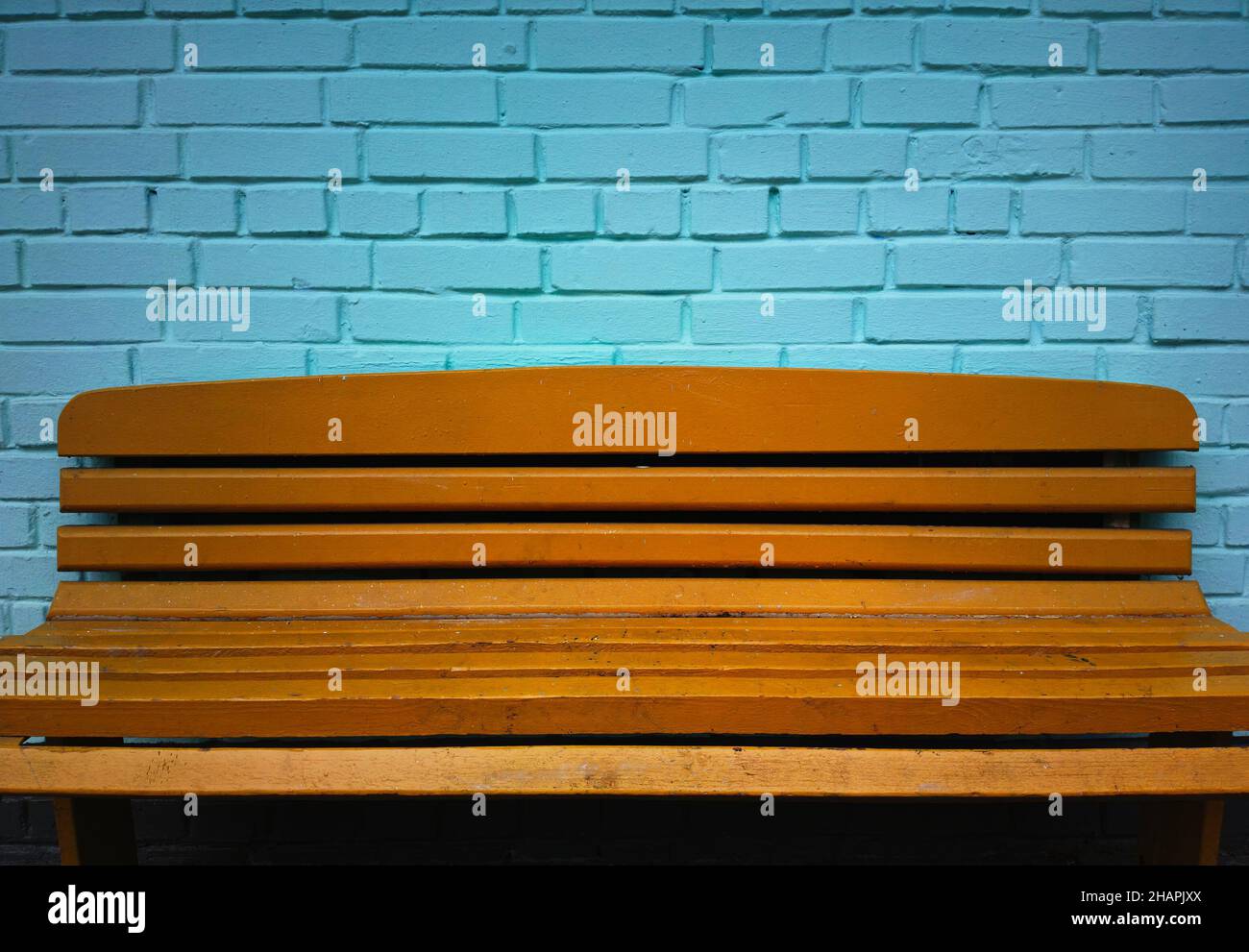 Orange bench with aqua cyan bricked wall Stock Photo - Alamy