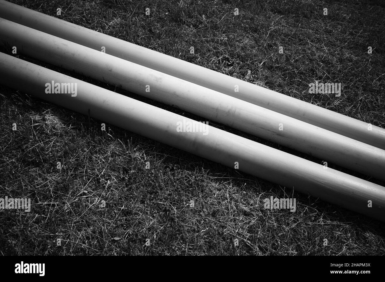 Diagonal pipes on the green grass background Stock Photo - Alamy