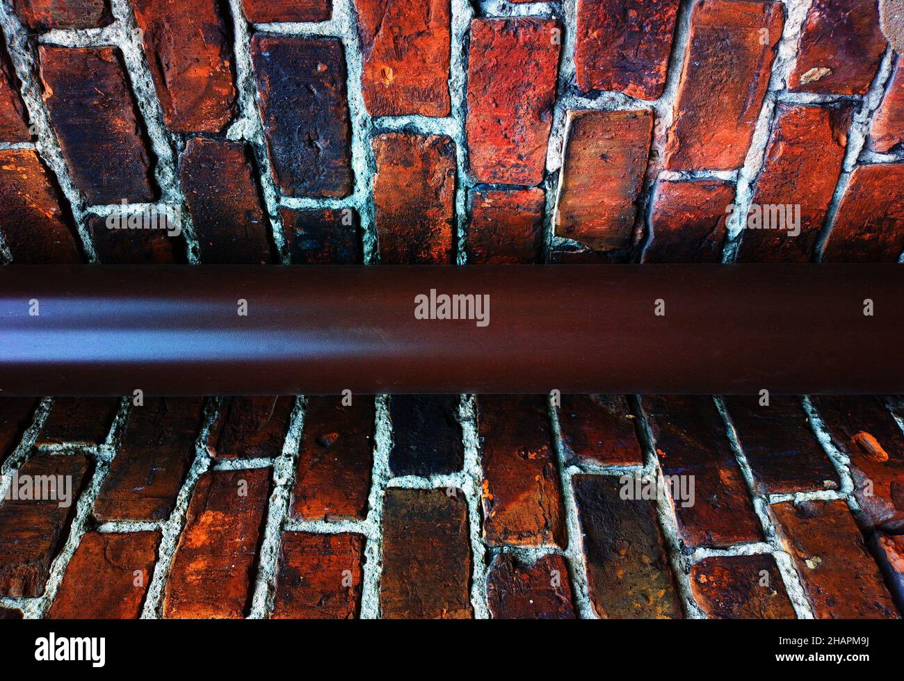 Horizontal brown pipe between red brick wall backdrop Stock Photo - Alamy