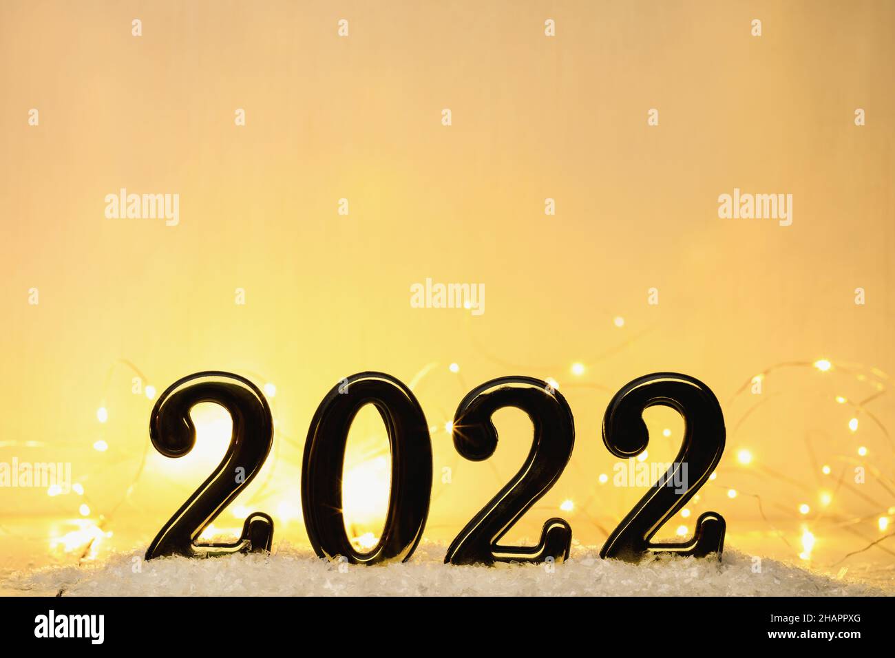 Black numbers 2022 on yellow background and luminous garland. New year ...