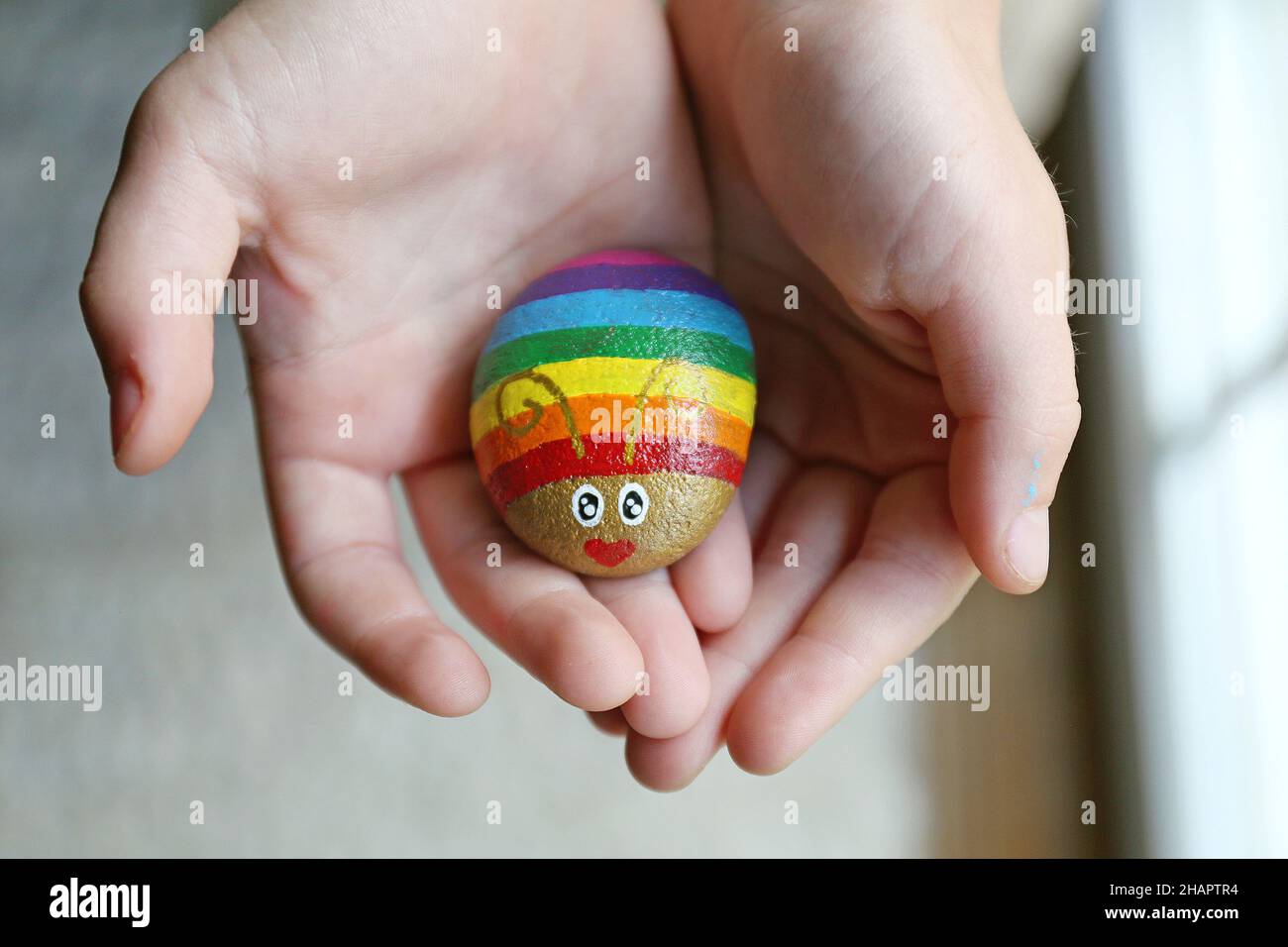 The little hands of a young child are gently holding onto a rock ...