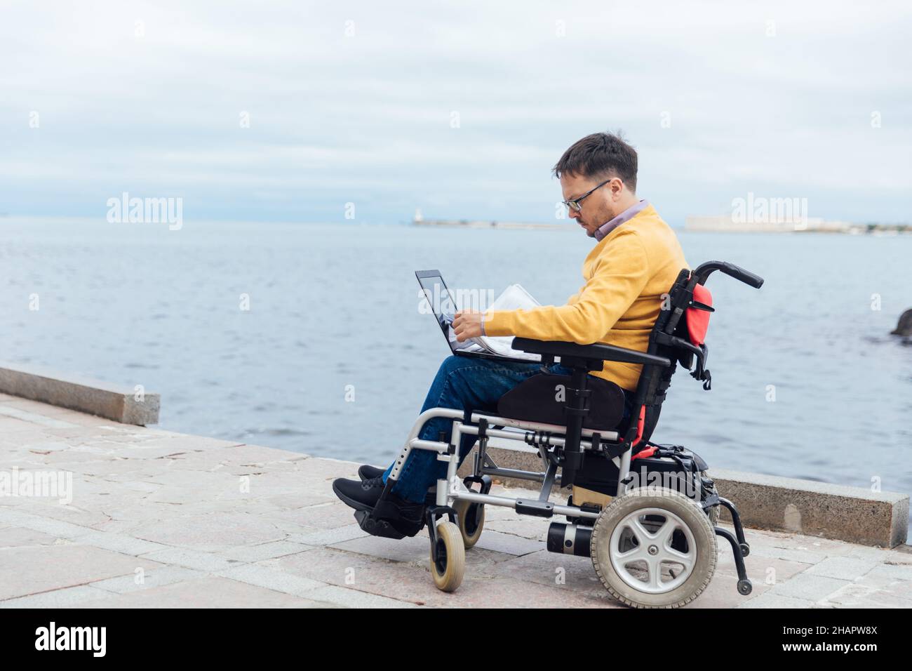 a man with disabilities in a wheelchair works on a computer on the ...
