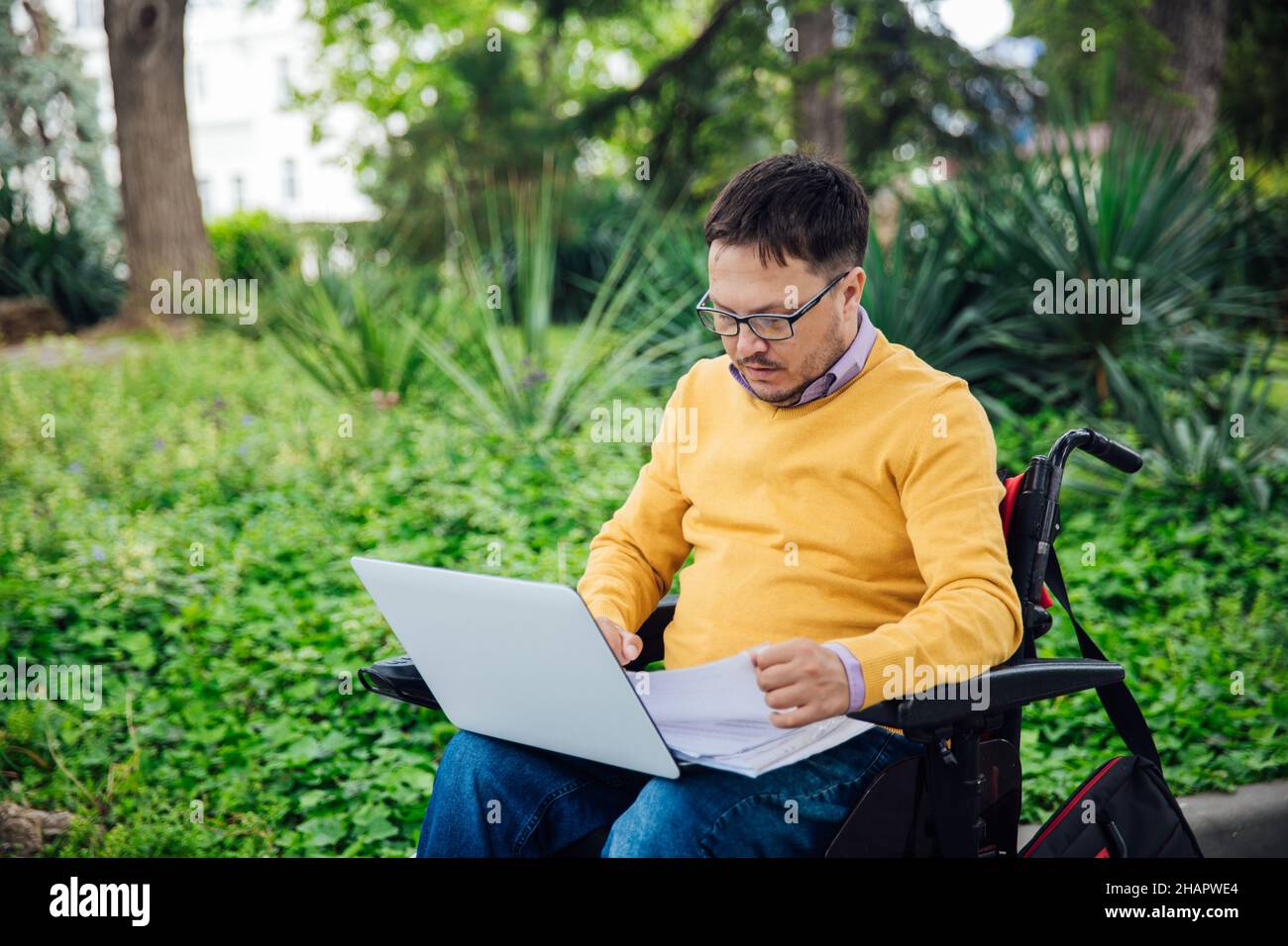 a man with disabilities in a wheelchair works at a computer on the ...