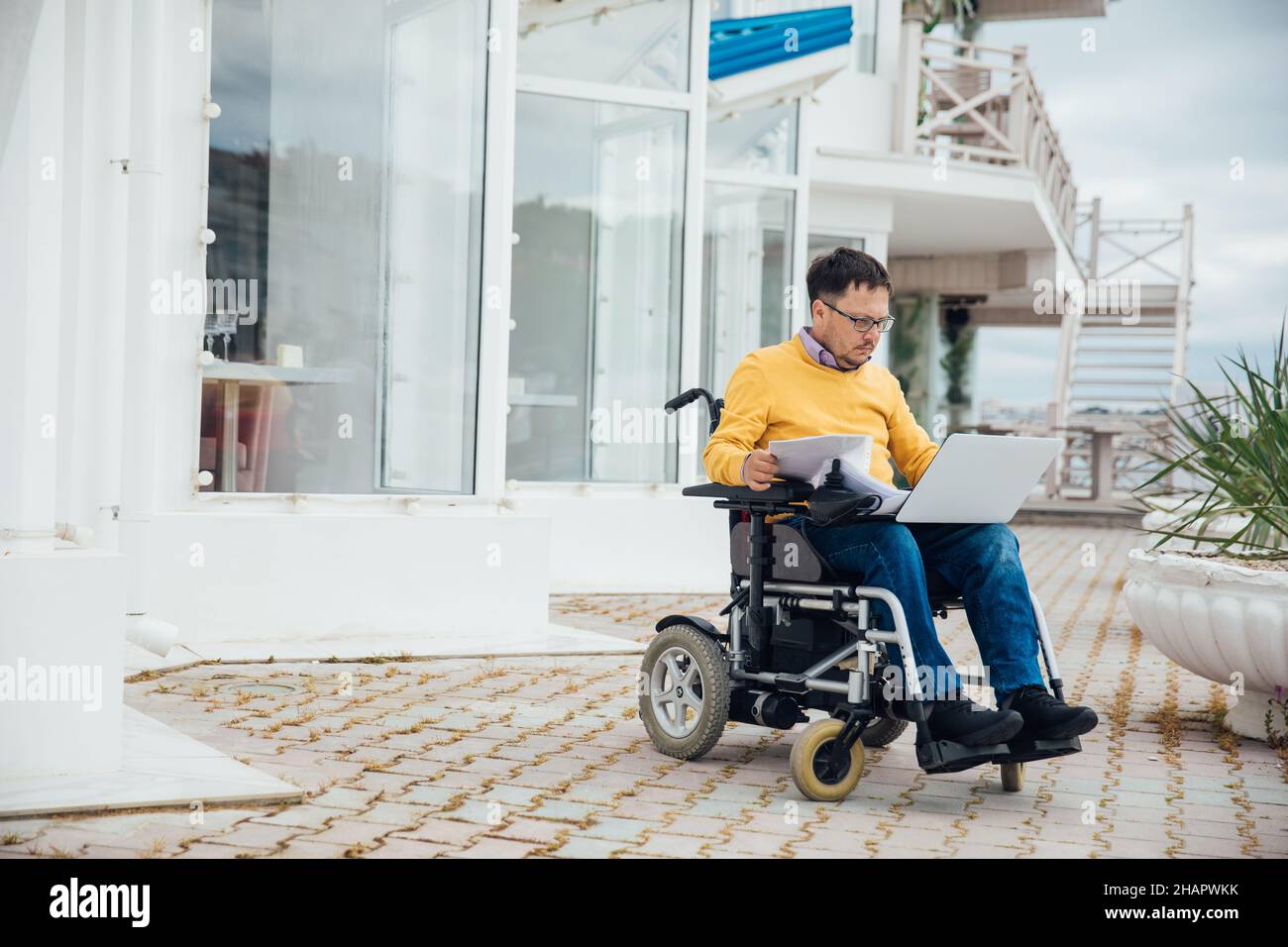 a man with disabilities in a wheelchair works at a computer on the ...