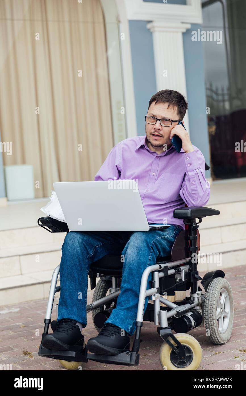 a man with disabilities in a wheelchair talking on a smartphone Stock ...