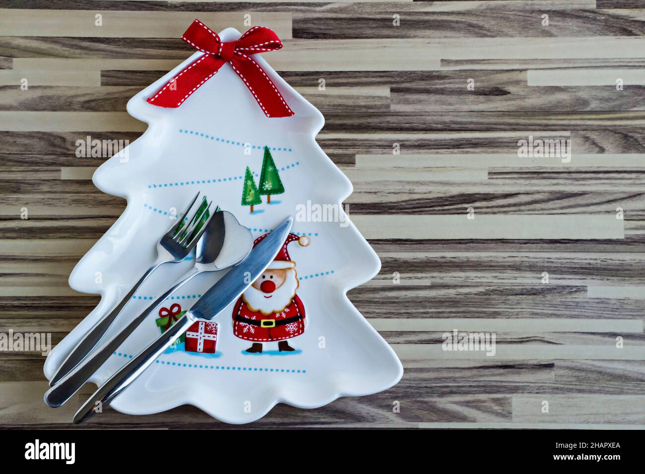 Porcelain plate in the shape of a christmas tree and cutlery set on ...