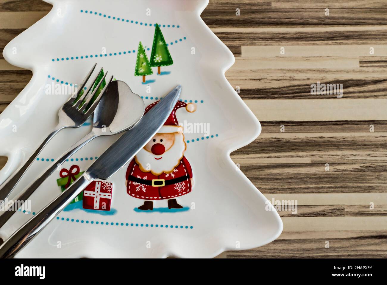 Porcelain plate in the shape of a christmas tree and cutlery set on ...